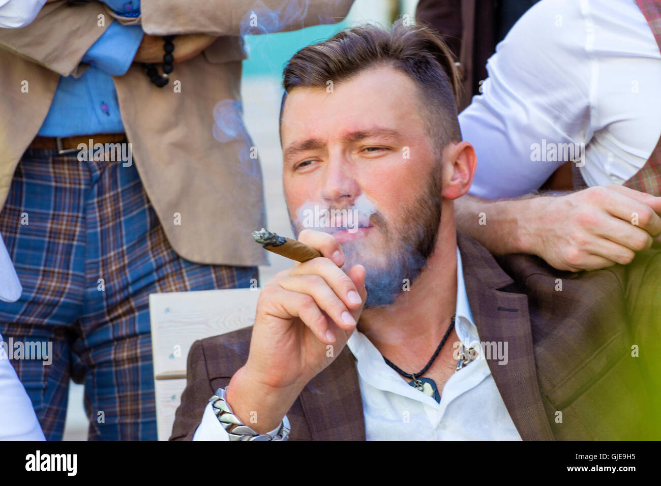 Elegant bearded man smoking a cigar outdoors Stock Photo - Alamy