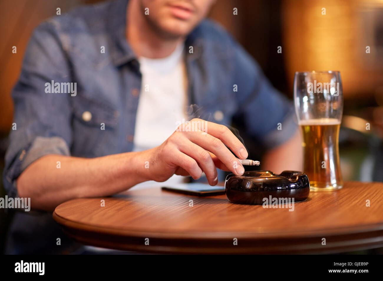man drinking beer and smoking cigarette at bar Stock Photo - Alamy