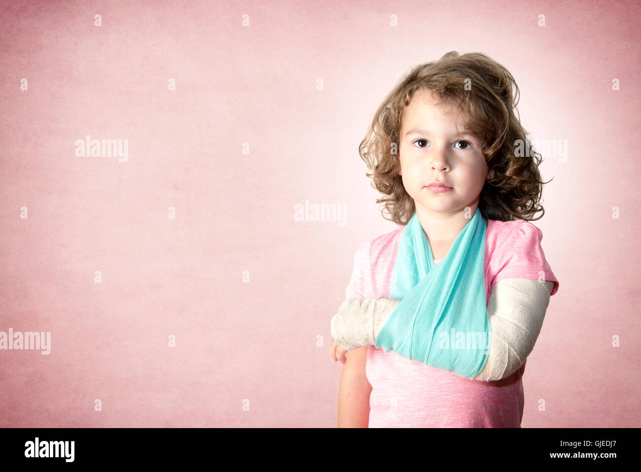 Little sad child with the broken hand on pink background with blank ...