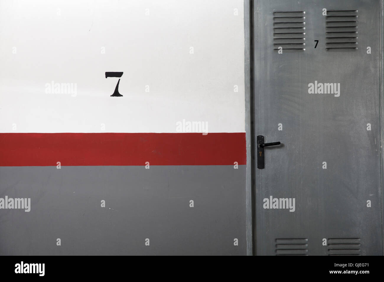 Grey door and painted wall in grey,white and red lines with number ...