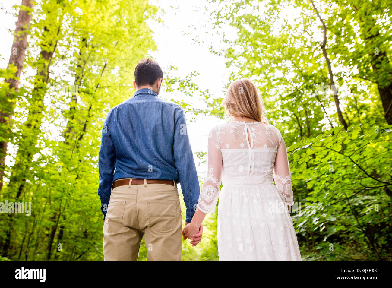 Beautiful wedding couple outside in green forest. Rear view Stock Photo ...