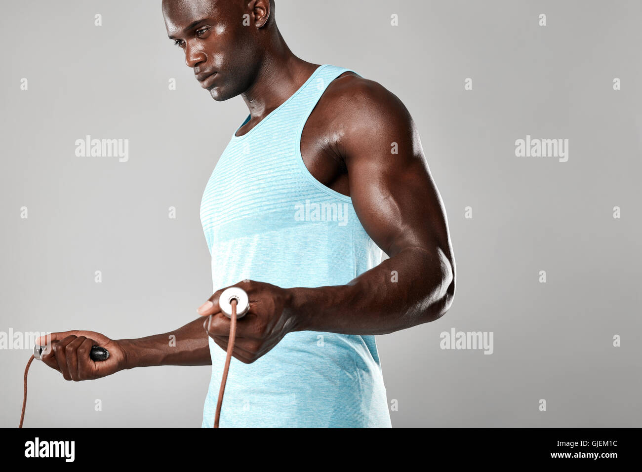 Shot of masculine man skipping rope. Muscular young man exercising with ...