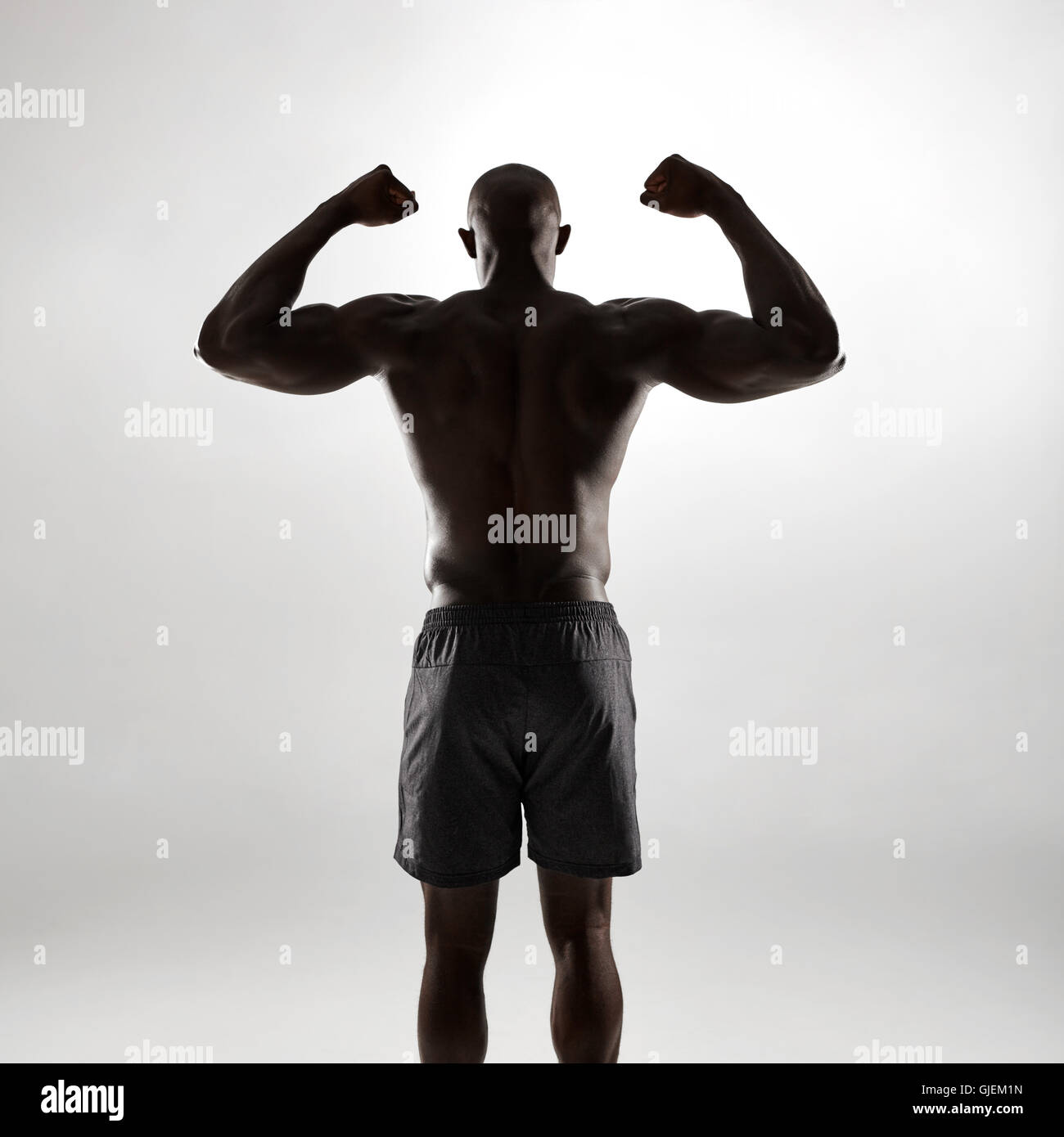 Rear view shot of young african male bodybuilder on grey background ...
