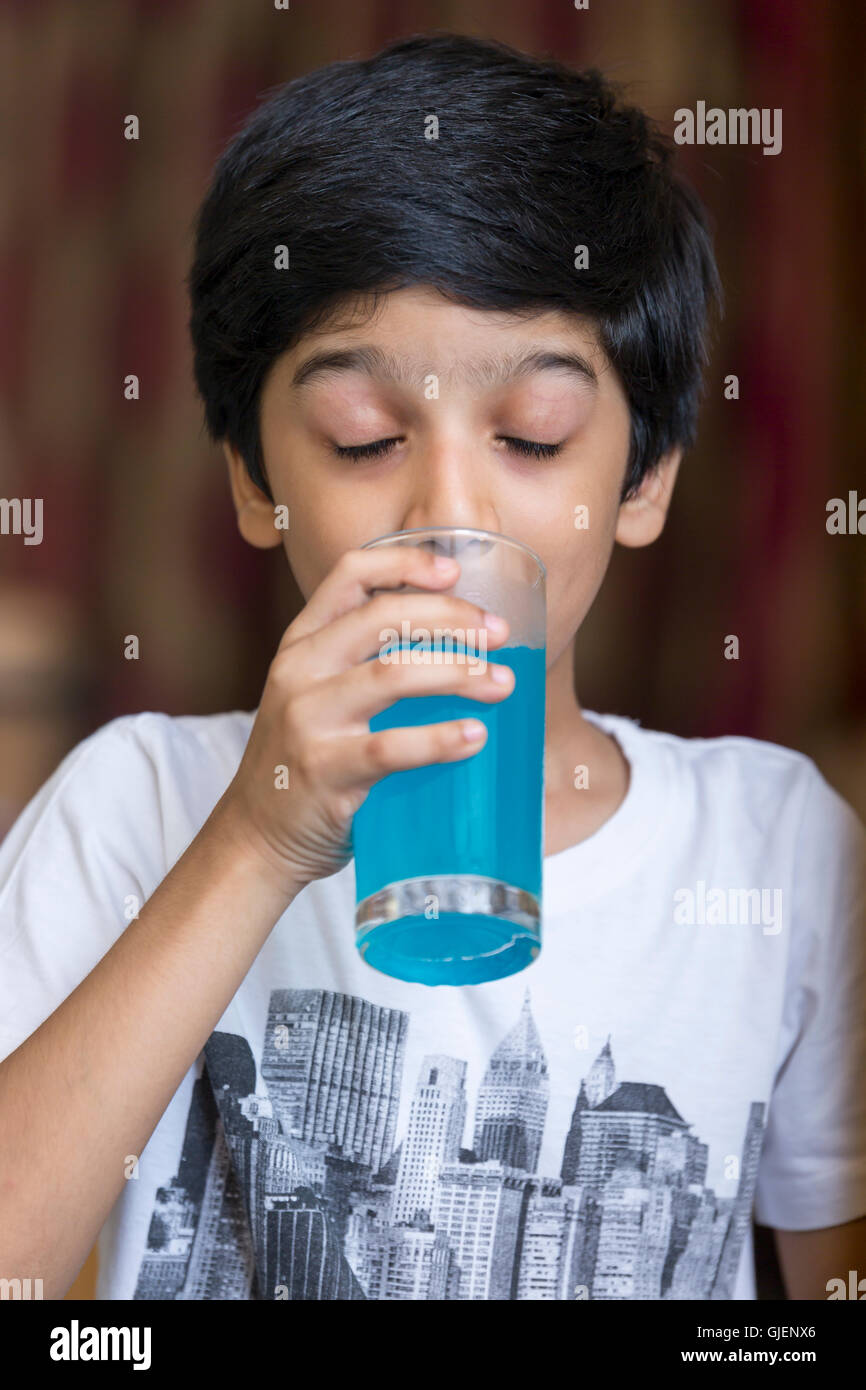 A young boy drinks a blue colour liquid from glass Stock Photo - Alamy