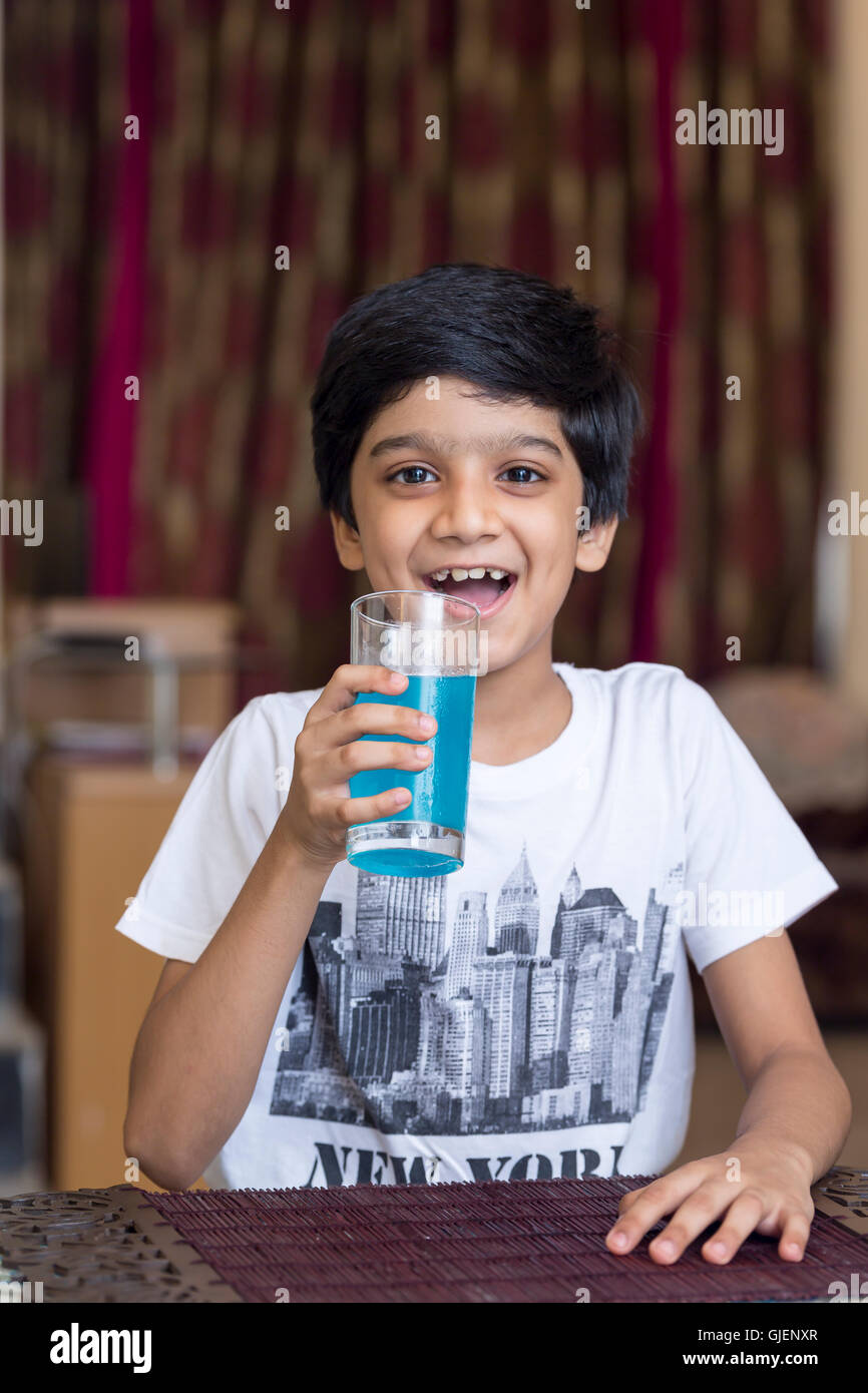 A young Indian boy holds a glass of a blue coloured health drink Stock ...