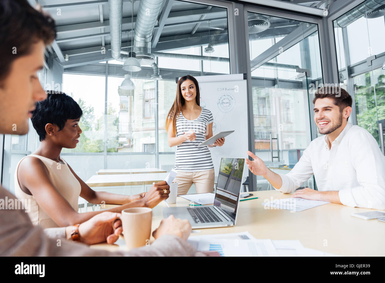 Happy pretty young woman standing and making presentation using ...