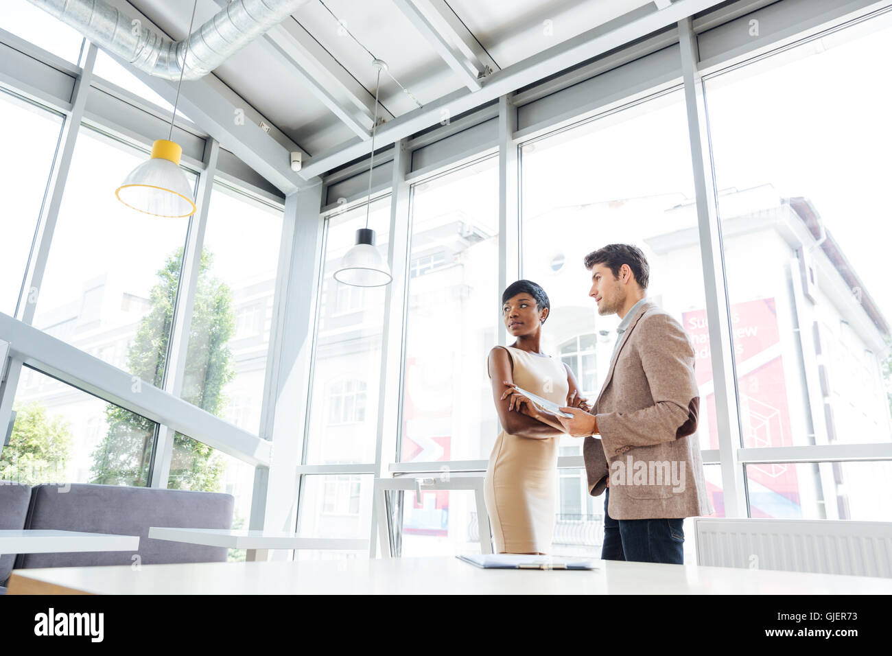 Two young business people standing and talking in office Stock Photo ...
