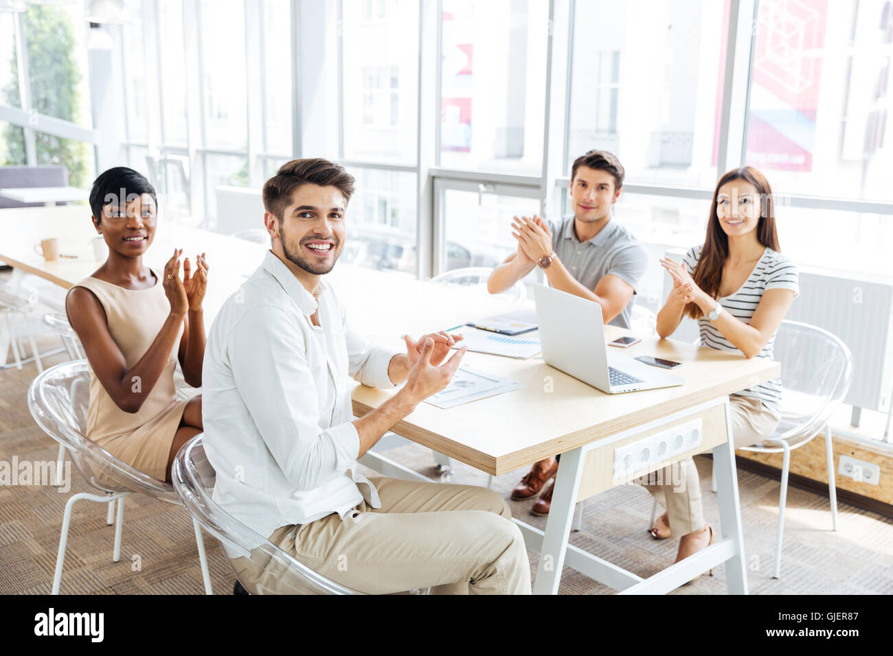 Multiethnic group of happy young business people clapping hands on ...