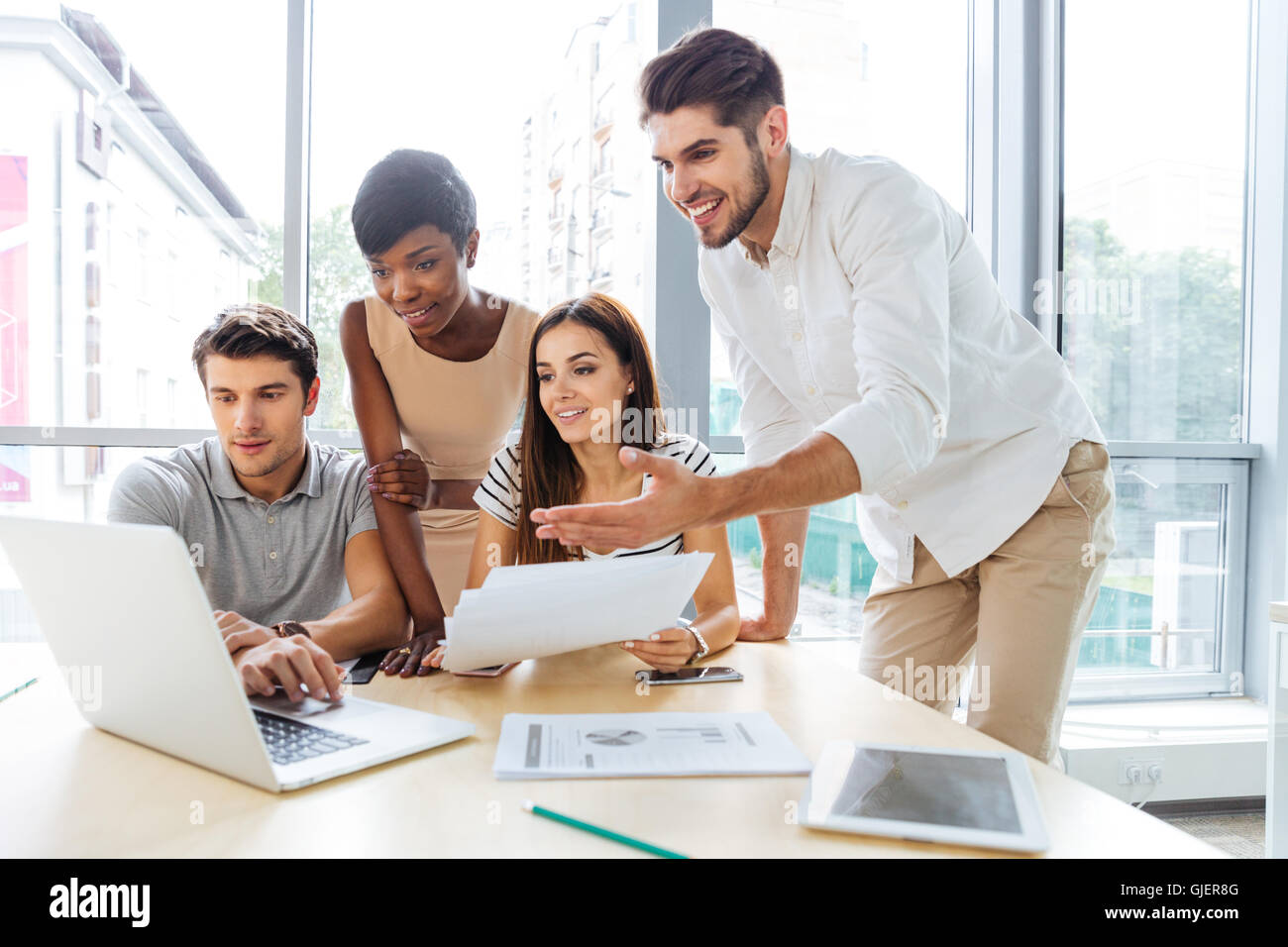 Group of happy young business people using laptop and working together ...