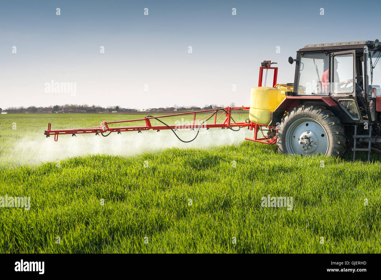 Tractor spraying wheat field with sprayer Stock Photo - Alamy