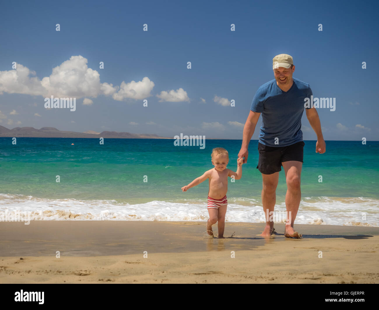 Father and son playing together on the beach during summer holidays ...