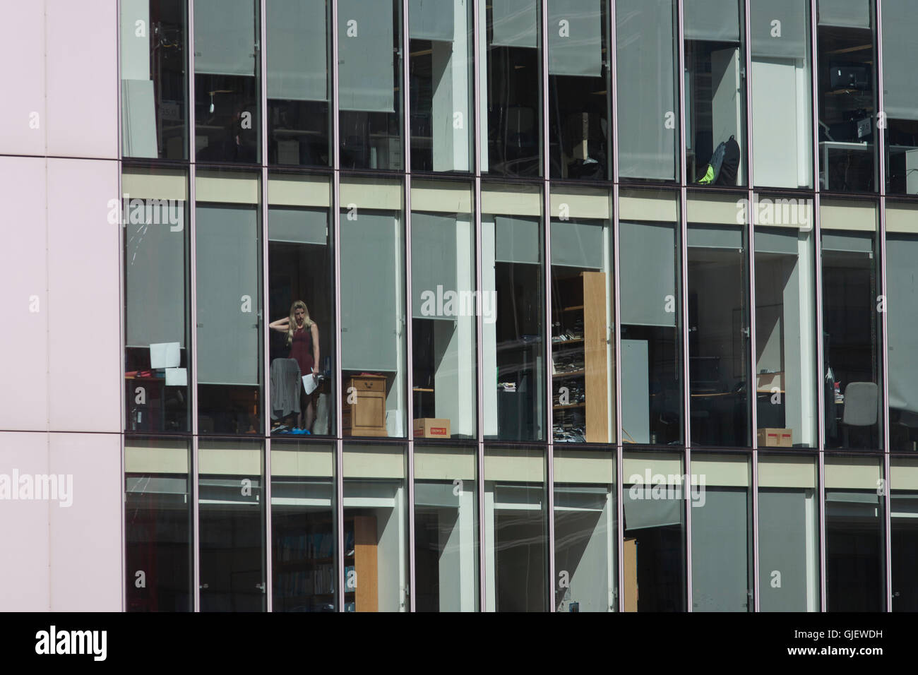 A female employee stares out the window of her office in the City of ...