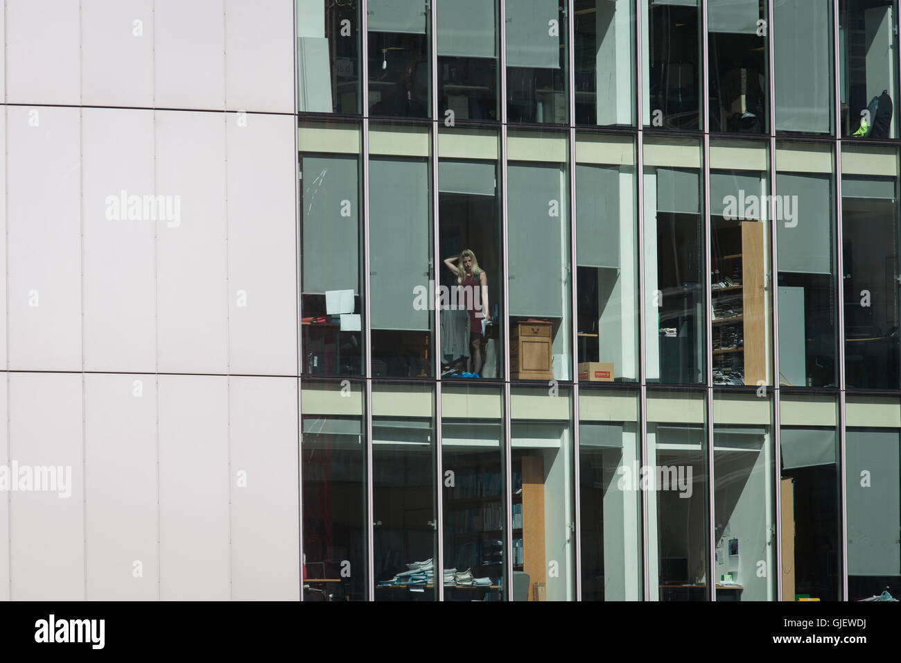 A female employee stares out the window of her office in the City of ...