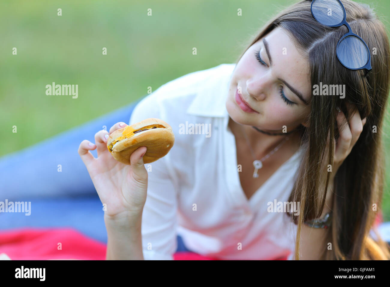 girl lying on the nature and eateth fast food. student working in the ...