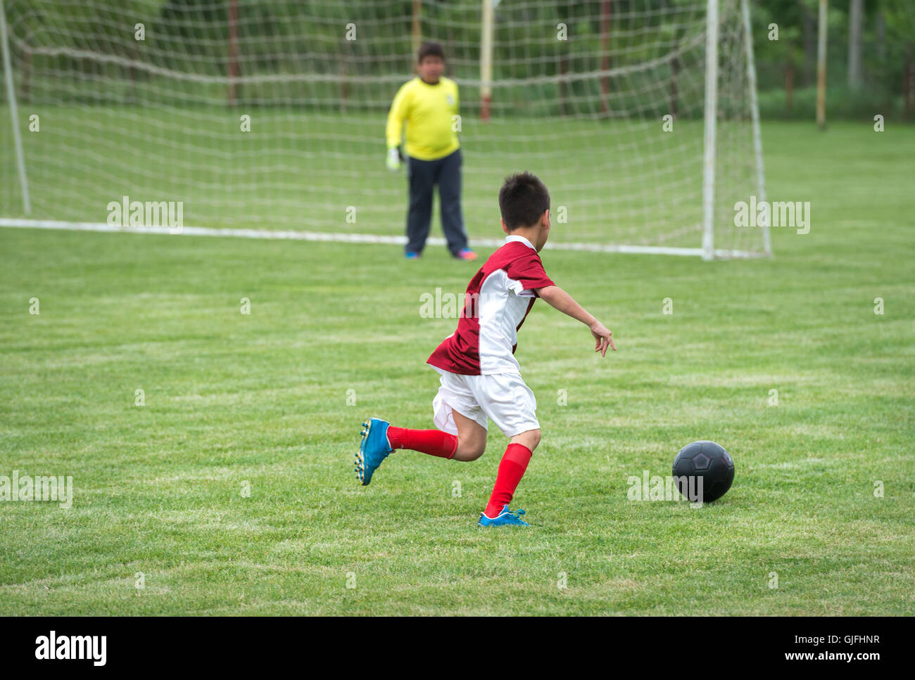 Boy kicking football on the sports field Stock Photo - Alamy