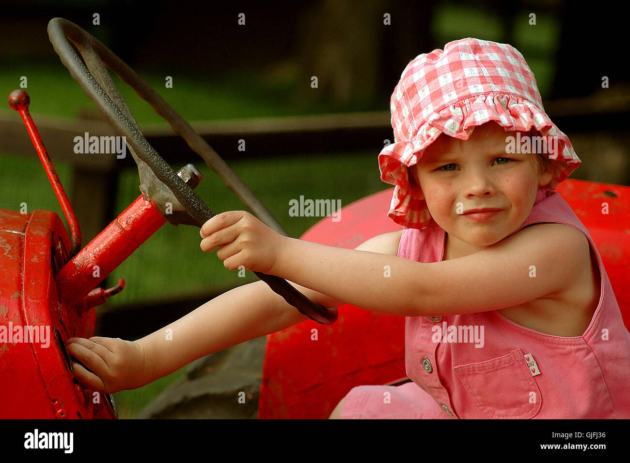 Young girl playing on an old farm tractor Stock Photo - Alamy