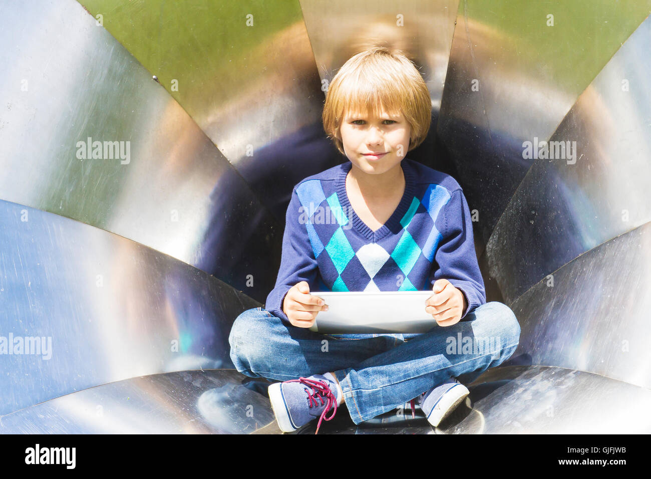 Little boy with tablet PC outdoor. Child looking straight. Metal ...