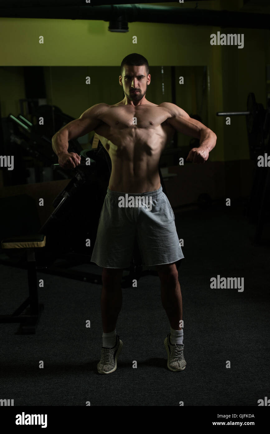 Young Man Standing Strong In The Gym And Flexing Muscles - Muscular ...