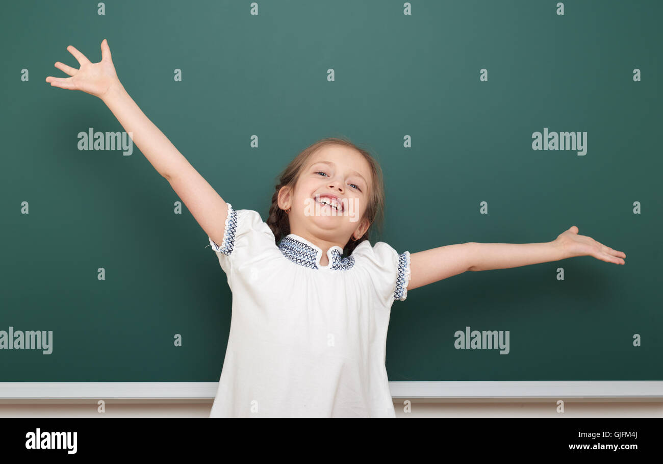 school student girl open arms at the clean blackboard, grimacing and ...