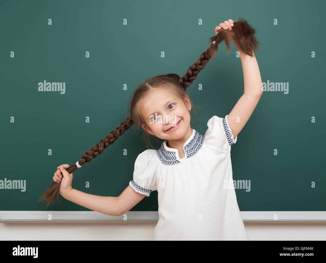 school student girl open arms at the clean blackboard, grimacing and ...