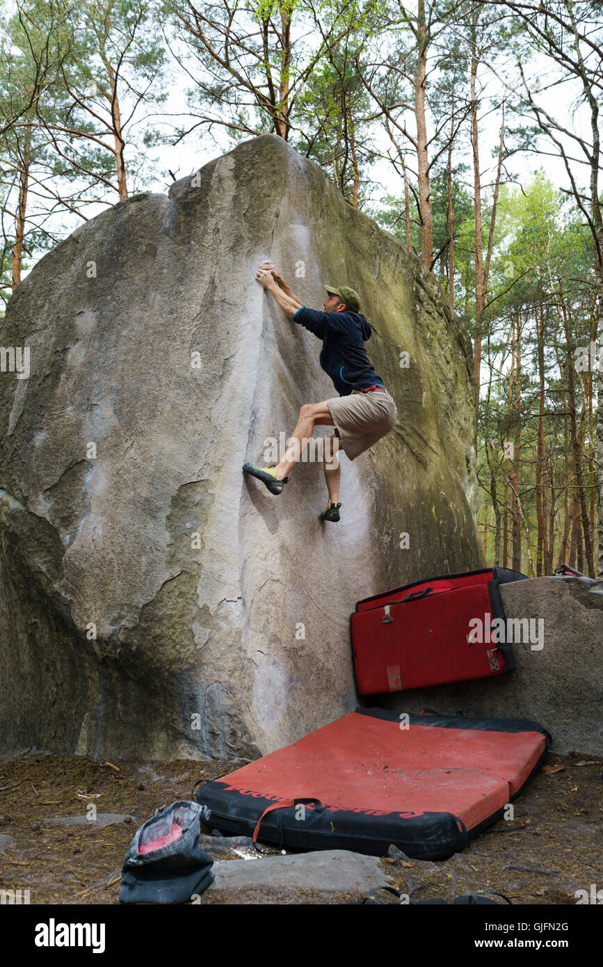 A man bouldering on the L'Angle Ben boulder problem in Fontainebleau ...