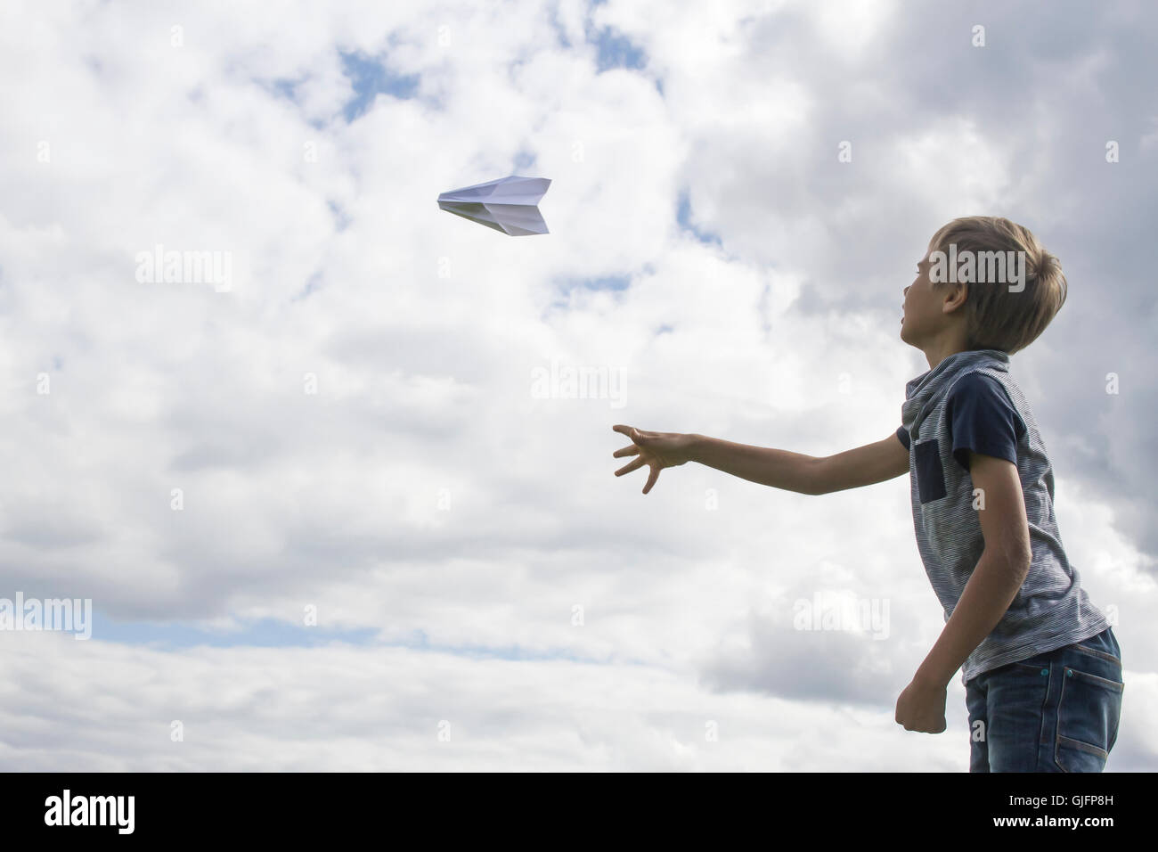Boy flying a paper plane against blue sky Stock Photo - Alamy