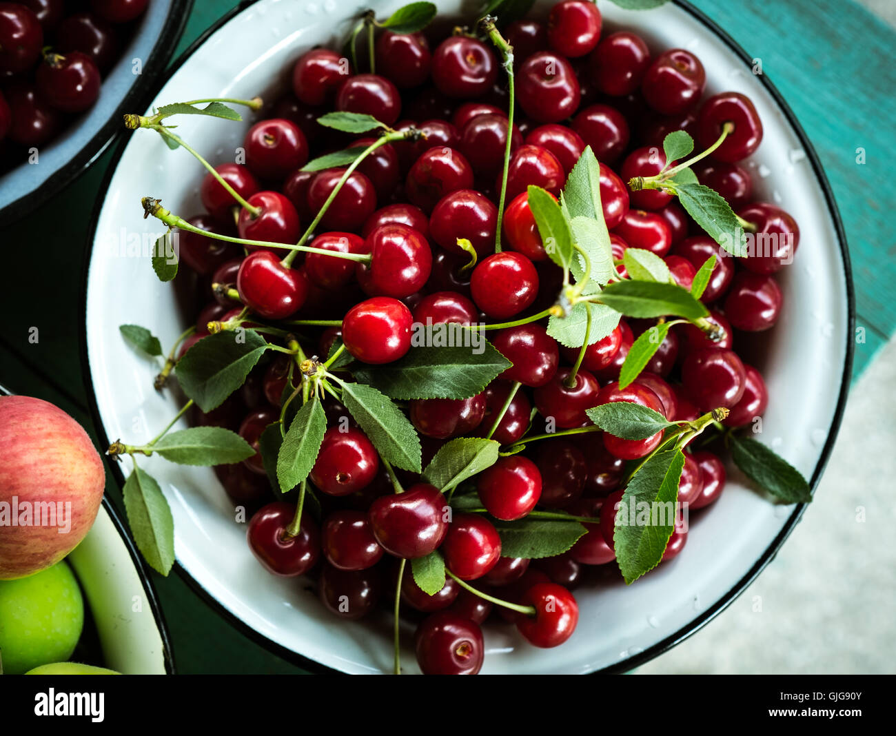 Bowl filled with Organic cherries on green table background Stock Photo ...