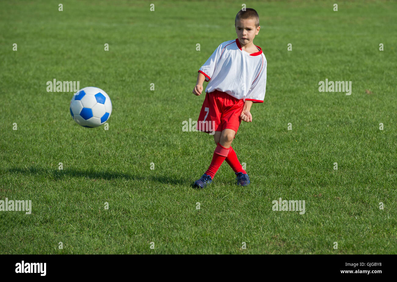 boy kicking football on the sports field Stock Photo - Alamy