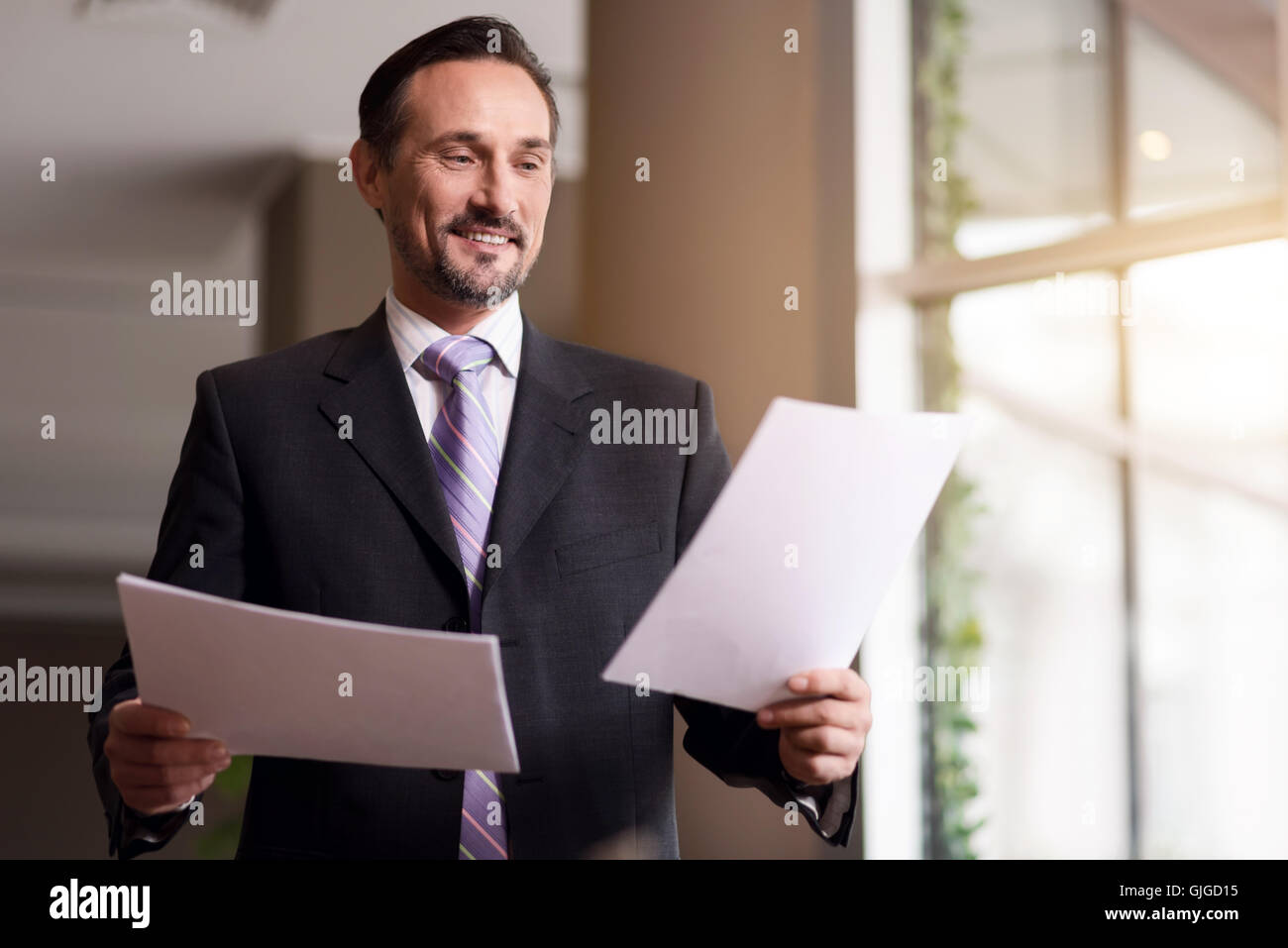 Positive businessman holding papers Stock Photo - Alamy