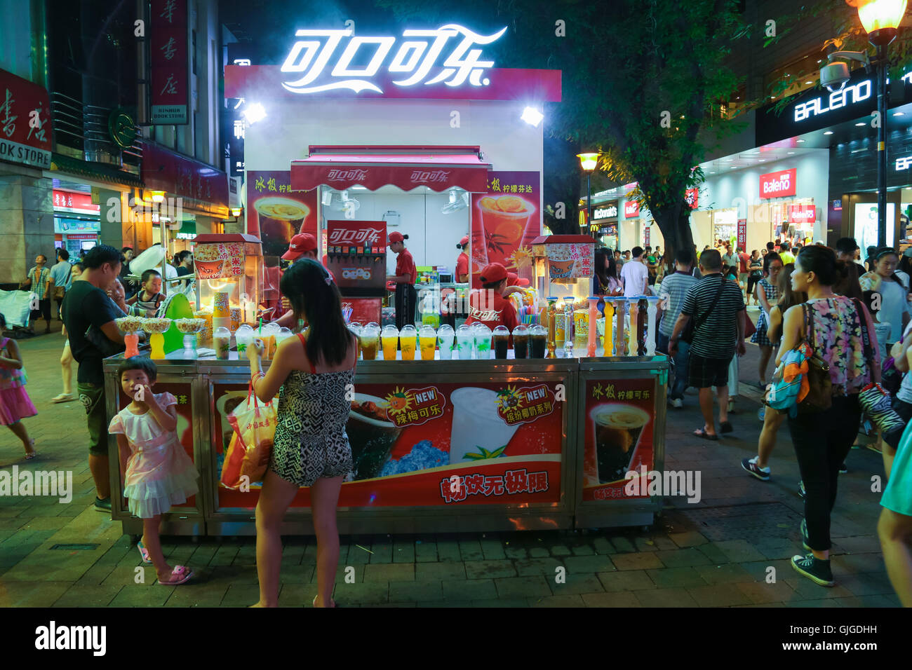 Locals buying iced drinks from beverage stall with Coca-Cola logo along ...