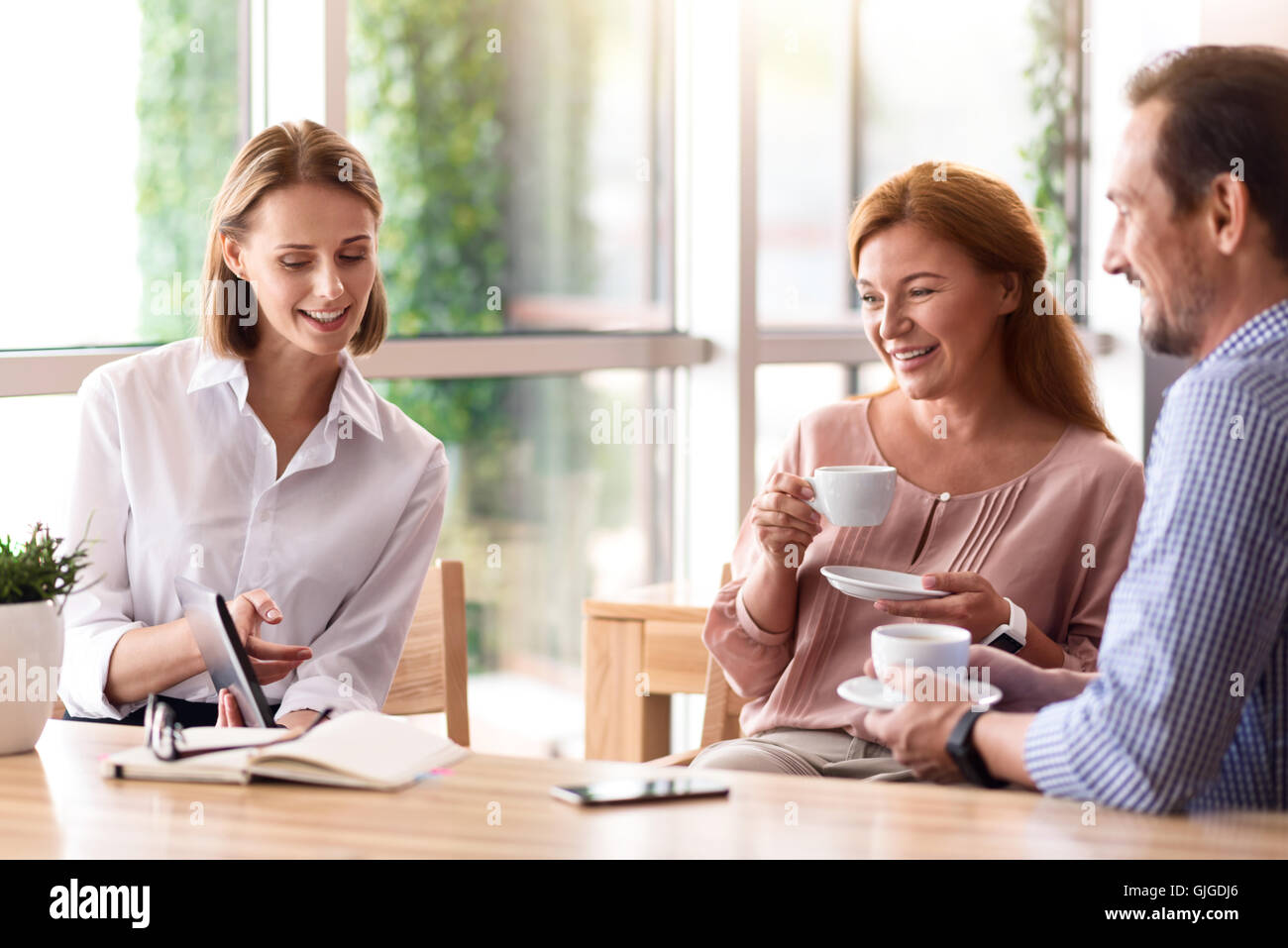 Delighted smiling colleagues drinking coffee Stock Photo - Alamy