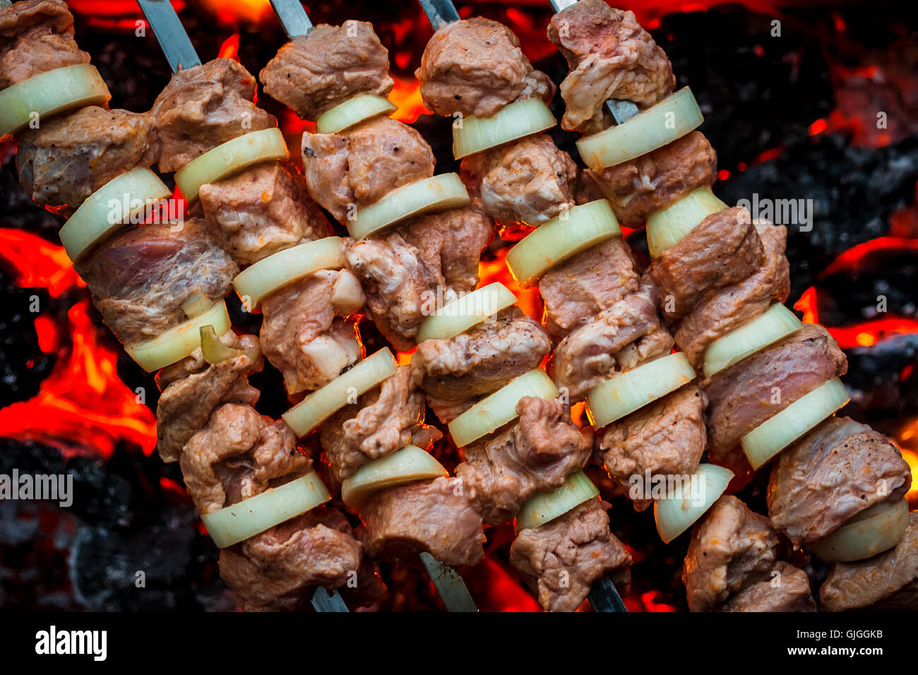 Barbecue pork kebabs on the hot grill close-up. Flames of fire and ...