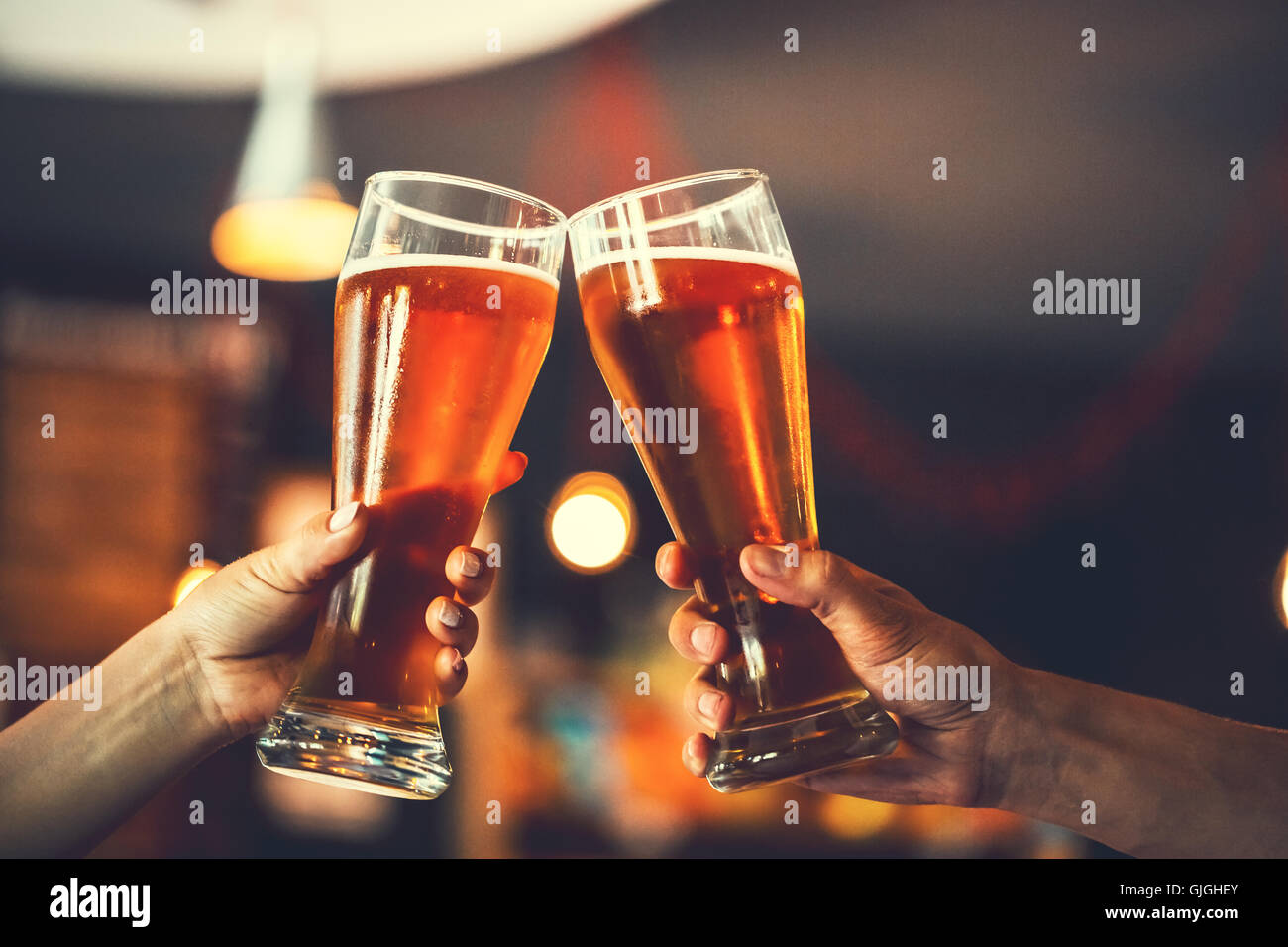 Two friends toasting with glasses of light beer at the pub. Beautiful ...