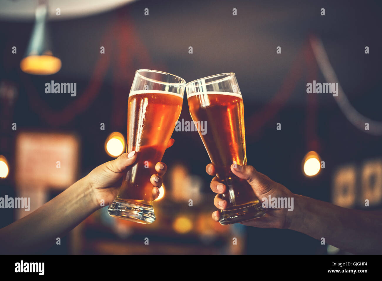 Two friends toasting with glasses of light beer at the pub. Beautiful ...