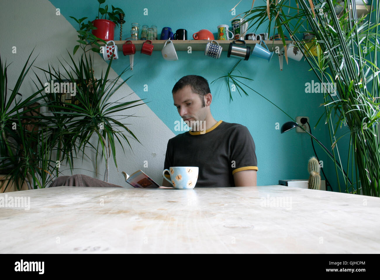young man sitting at the table reading Stock Photo - Alamy