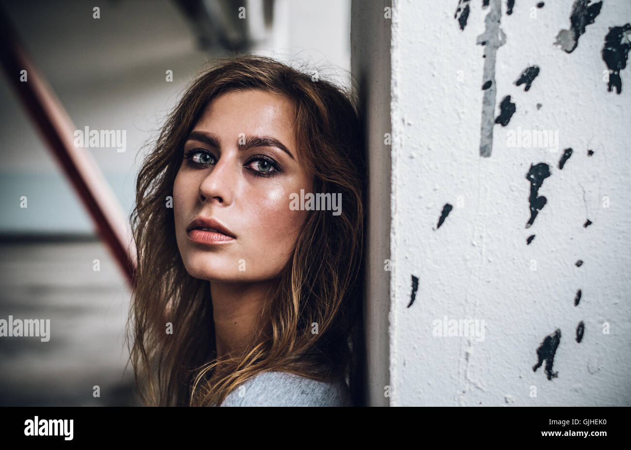 Portrait of a woman leaning against a wall Stock Photo - Alamy
