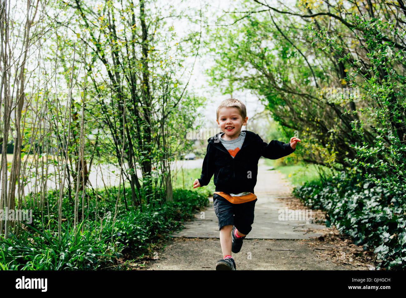 Boy running along pavement Stock Photo - Alamy
