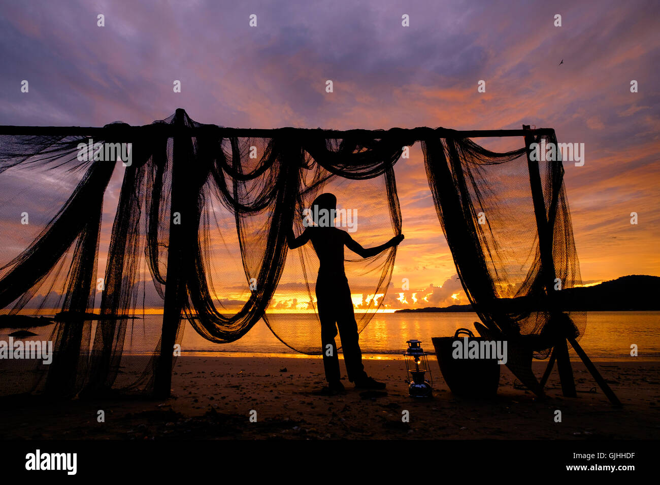 Silhouette of a man standing on beach by fishing nets hi-res stock ...