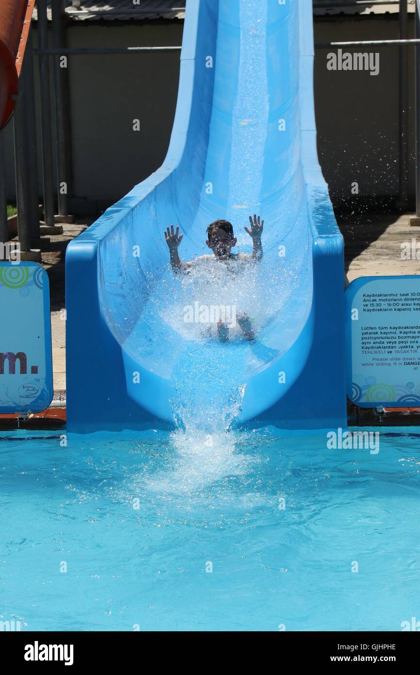 A young English boy having fun on a water slide in a waterpark while on ...