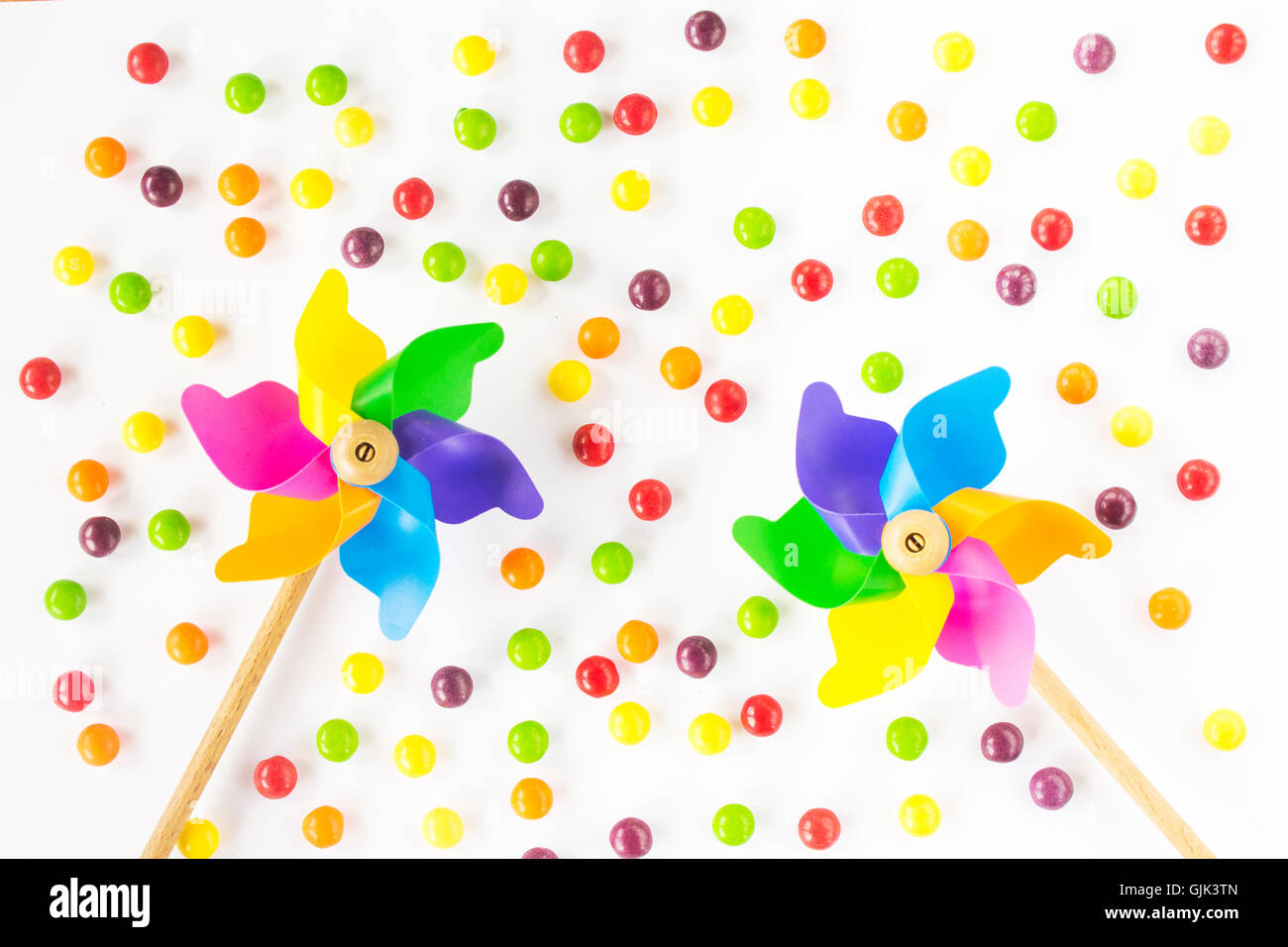 Colorful pinwheels and candies on white background. Top view. Flat lay ...