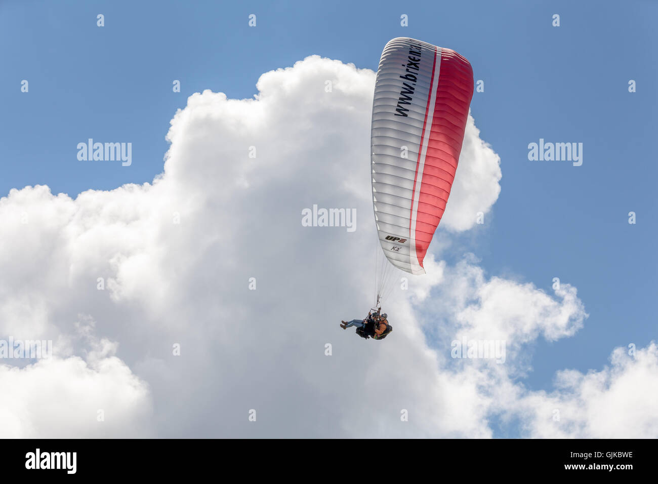 Paraglider flying seen from down with clouds and sky as a background at ...