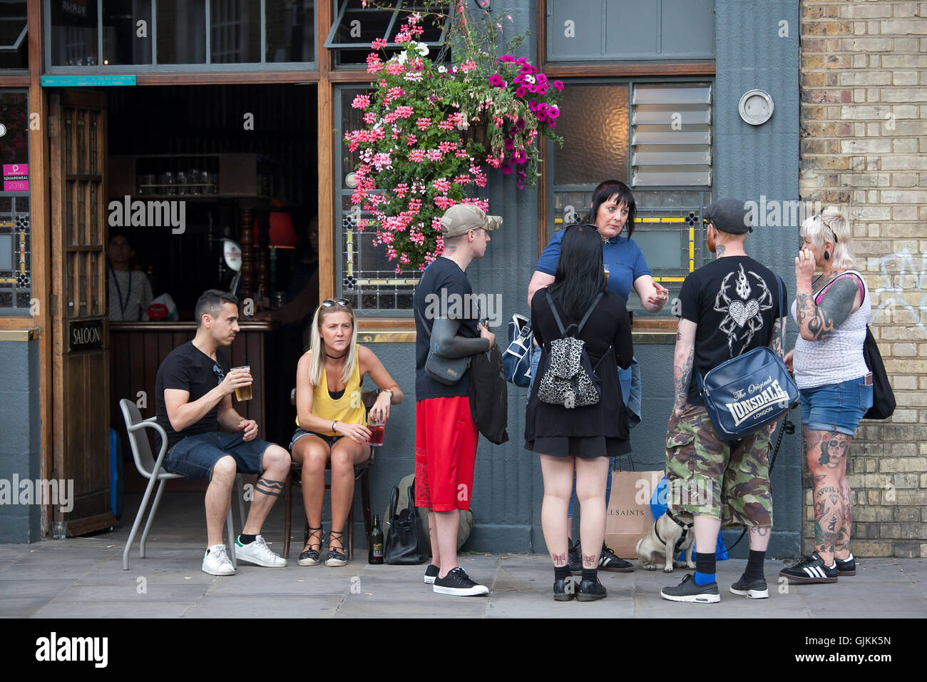 a motley crowd of East London drinking a beer outside of pub in London ...