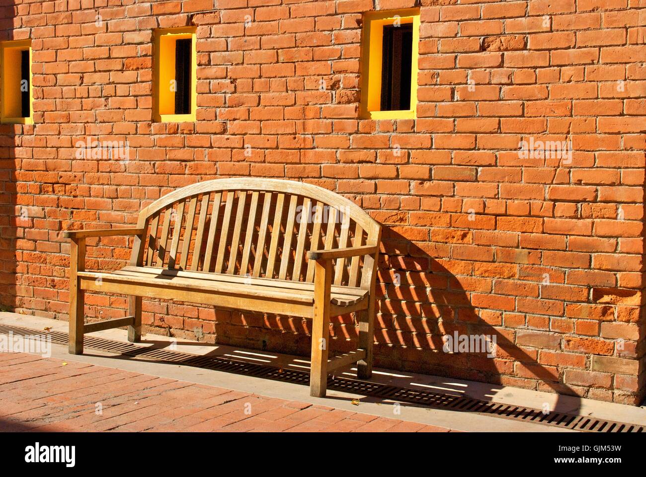 Wooden Bench Sitting by Orange Brick Wall with Yellow Windows Stock ...