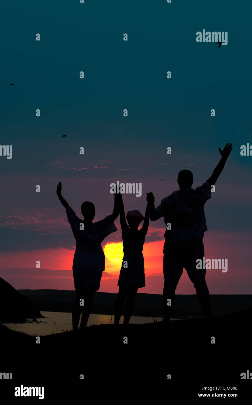 The family from three persons welcomes the sunset sun Stock Photo - Alamy