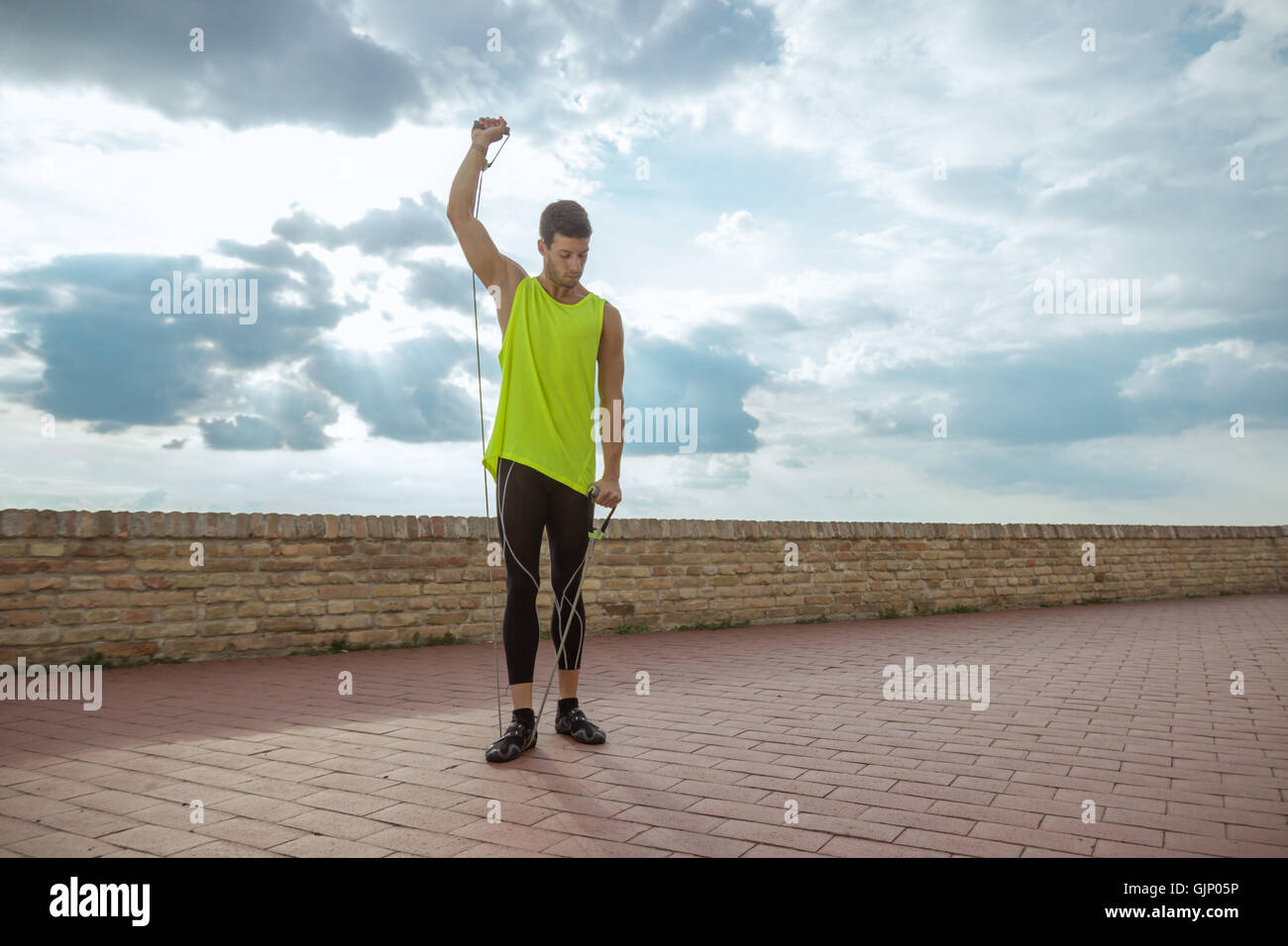Young fit man resistance band outdoors training arm up Stock Photo - Alamy