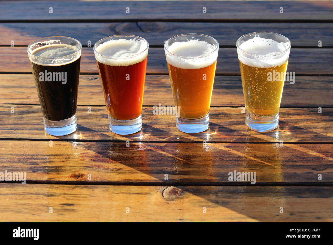 A selection of four craft beers during a tasting session on a wooden ...