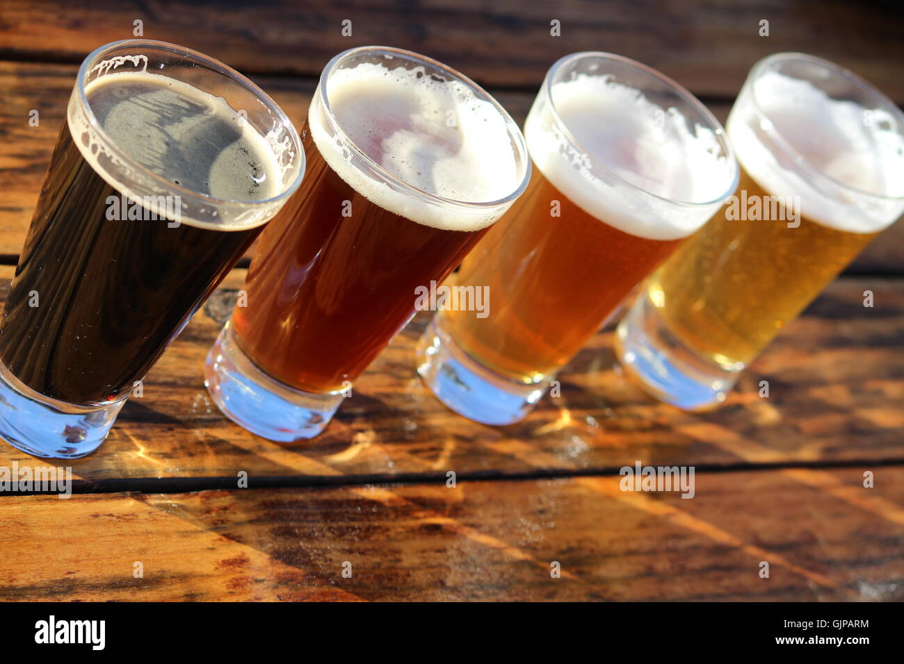 A selection of four craft beers during a tasting session on a wooden ...