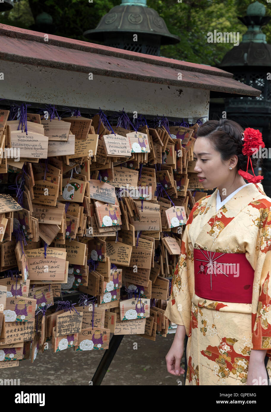 Woman dressed in traditional kimono looks at Ema wish plaques at Ueno ...