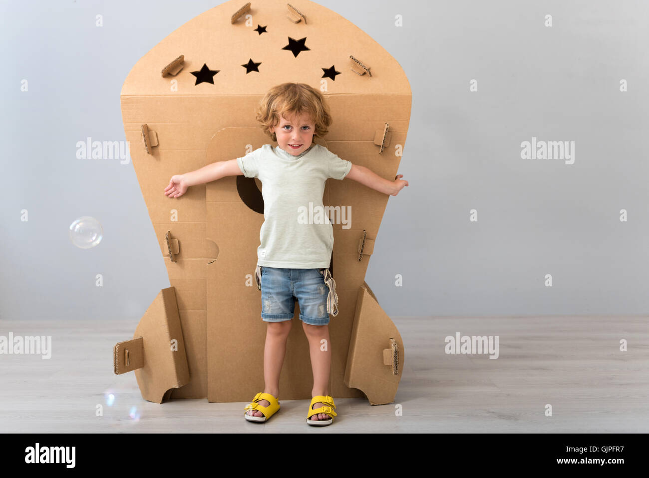 Little boy standing near carton rocket Stock Photo - Alamy