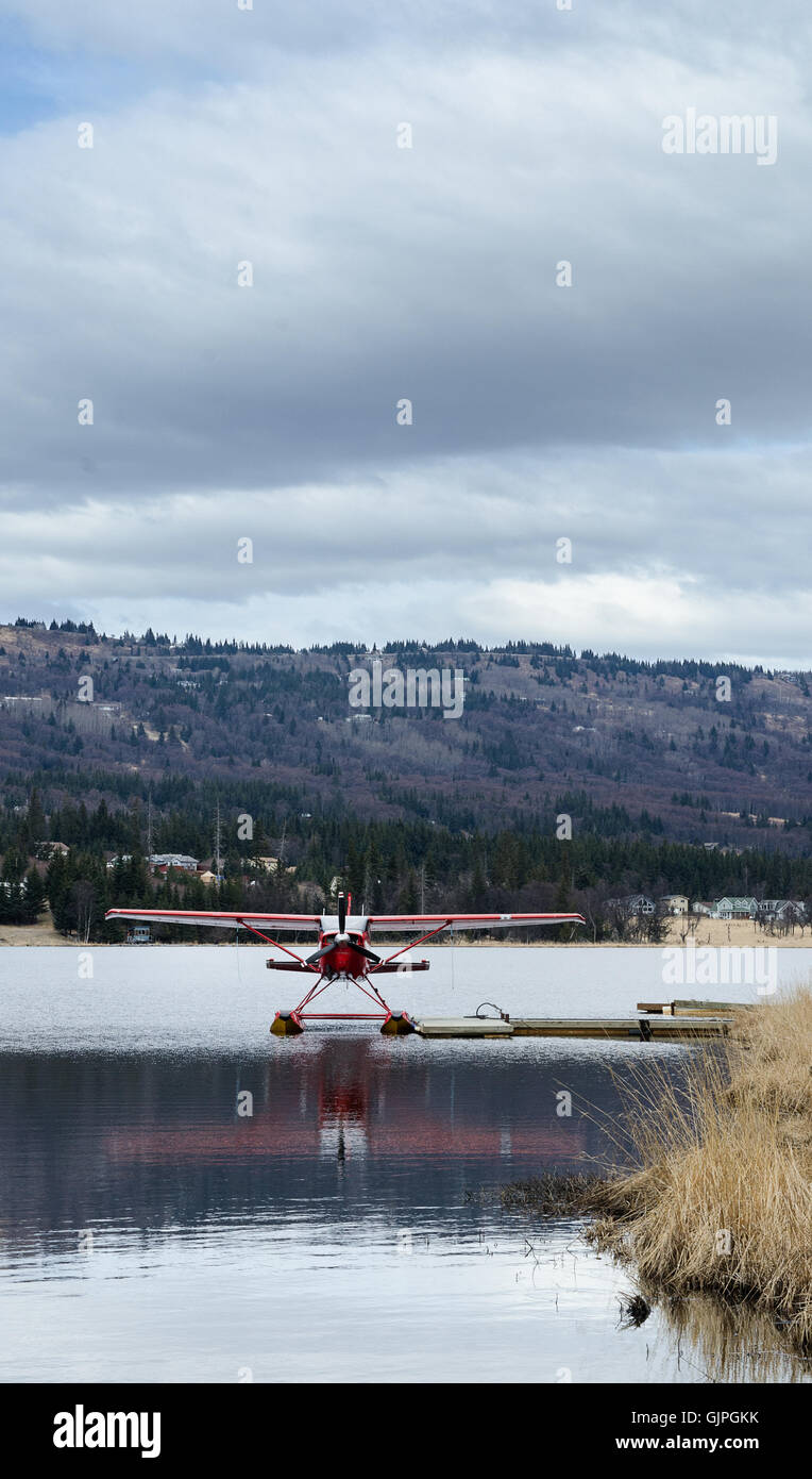 A red sea plane is docked on a still lake Stock Photo - Alamy